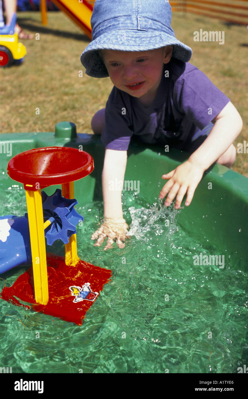 CHILD PLAYING IN paddling pool, with plastic waterwheel toy.HACKNEY ...