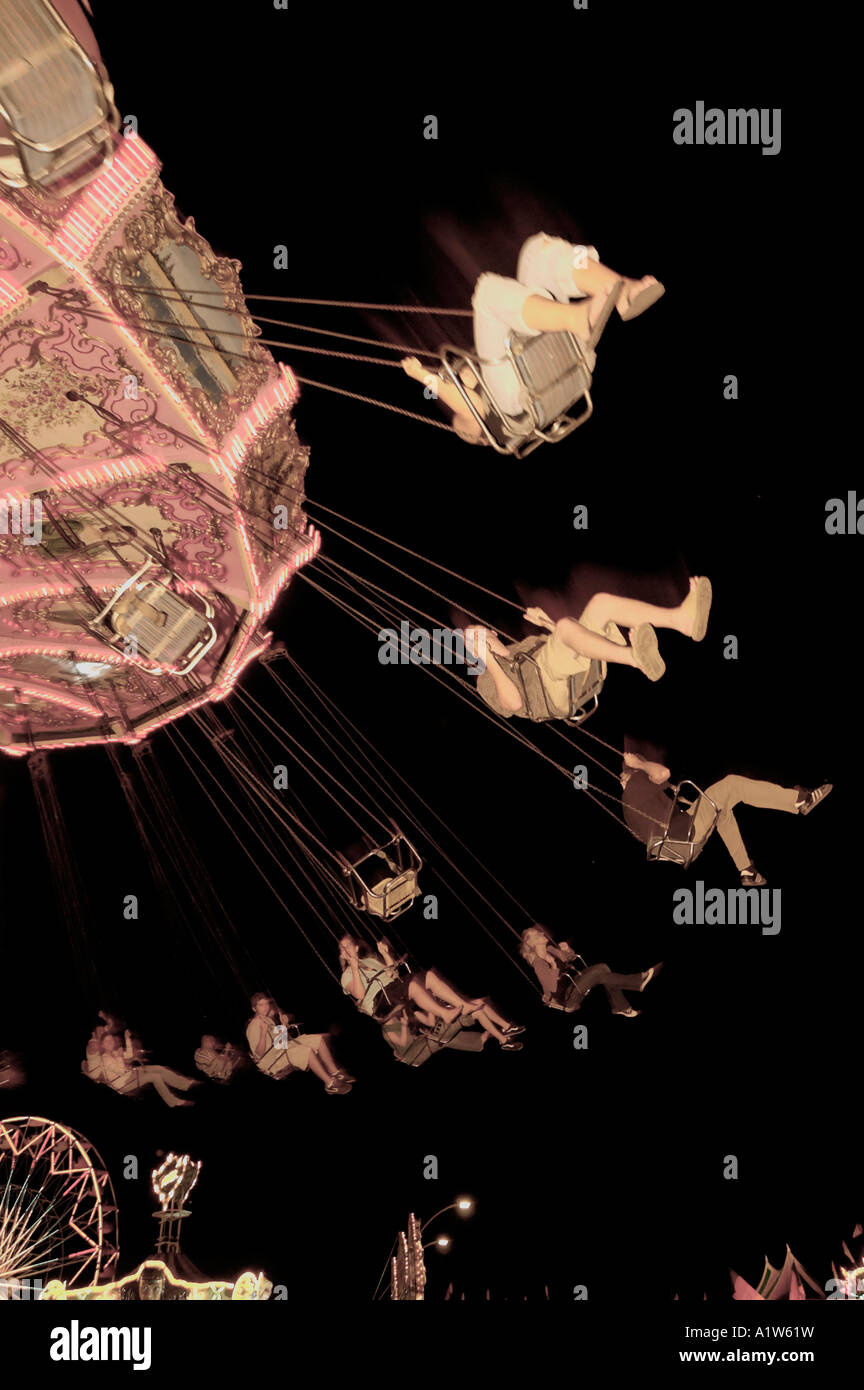 Tinted black and white image of carnival swing ride in motion at night ...