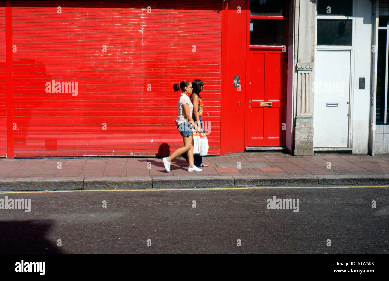 Two young Afro Carribean girls walk down Atlantic Road Brixton London ...