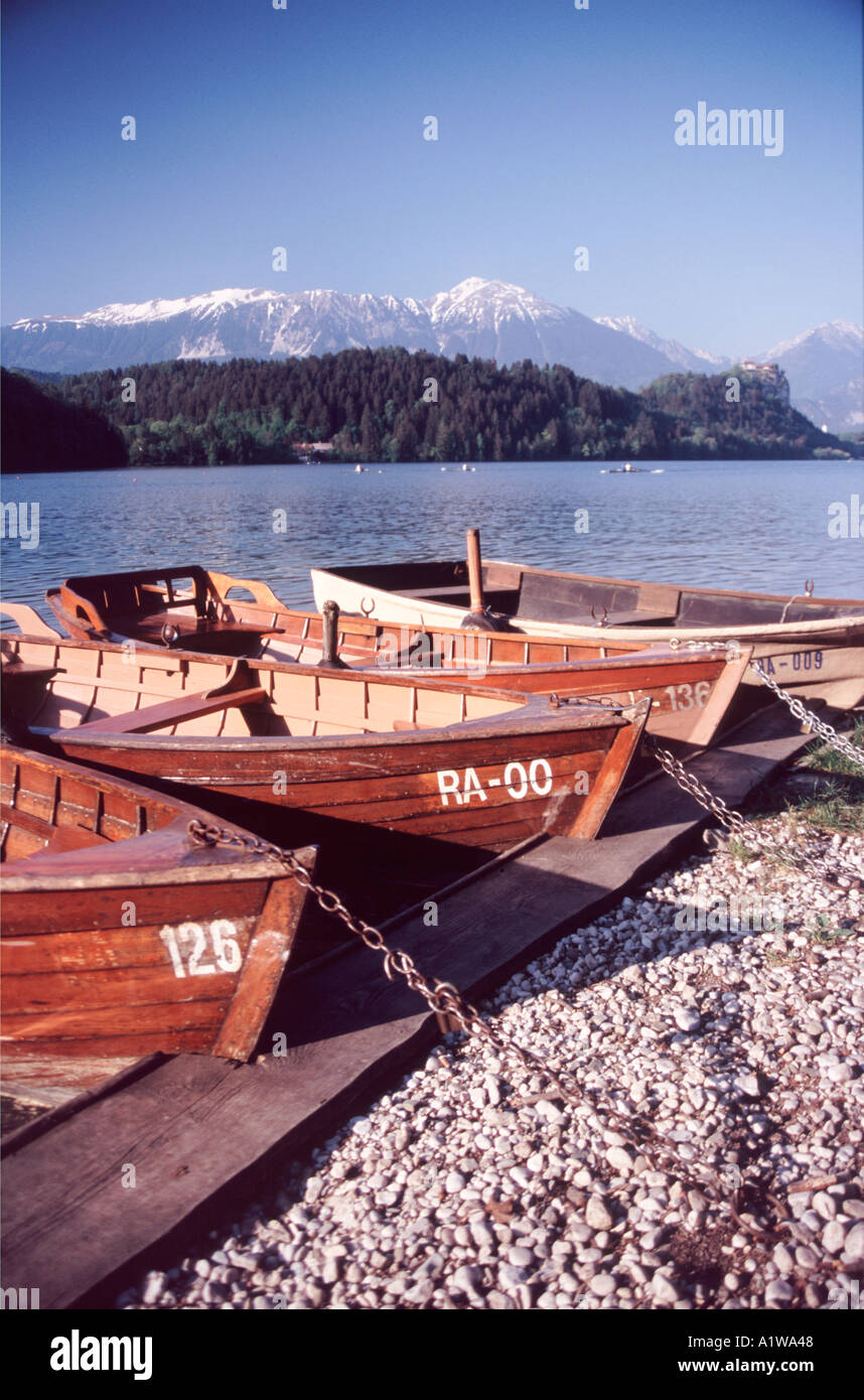 Rowing boats on lake Bled at sunset with mountains and castle in the ...