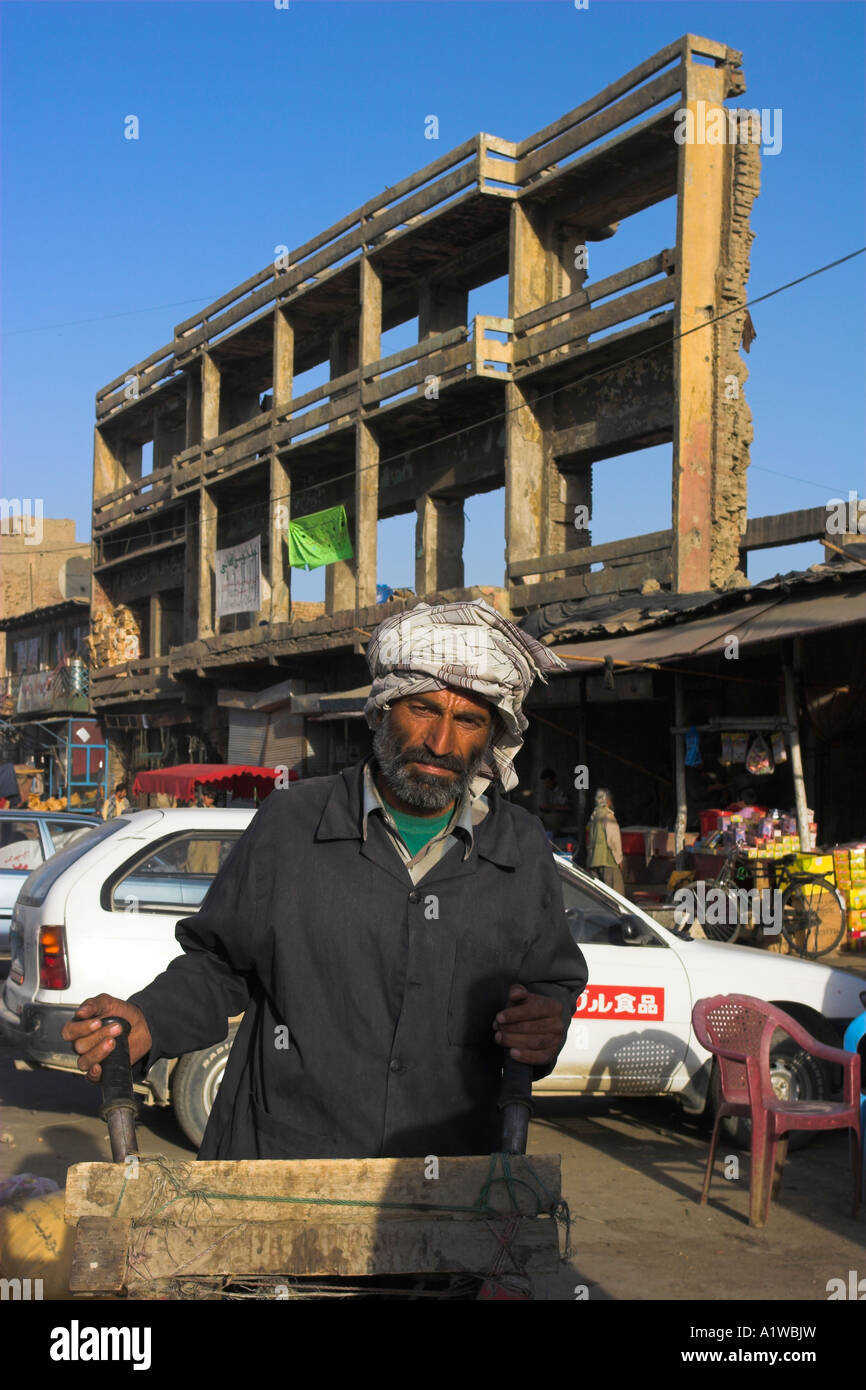 AFGHANISTAN Central Kabul Man pushing trolley near war damaged building ...