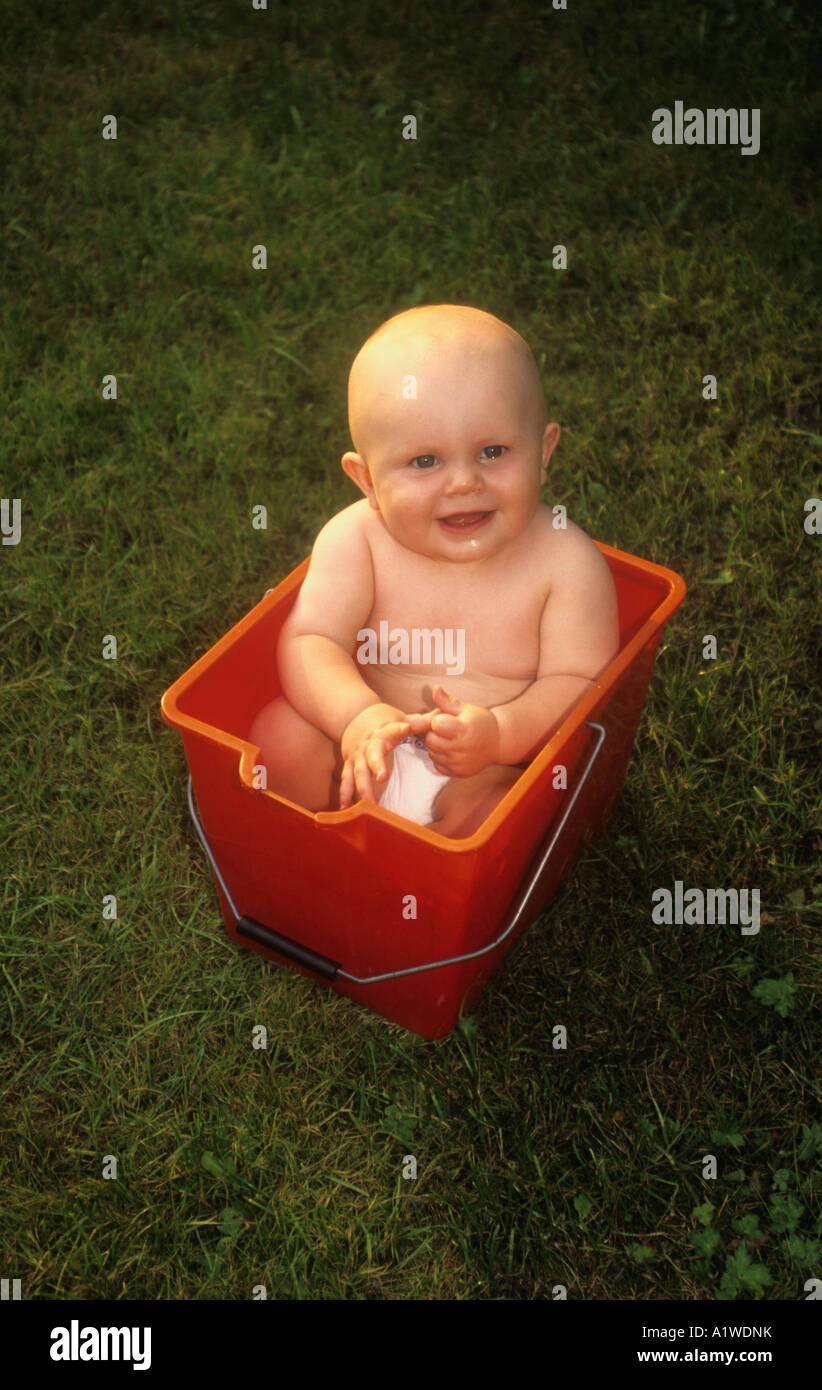Little Baby Boy Sitting In A Red Plastic Bucket , Outside On A Garden ...