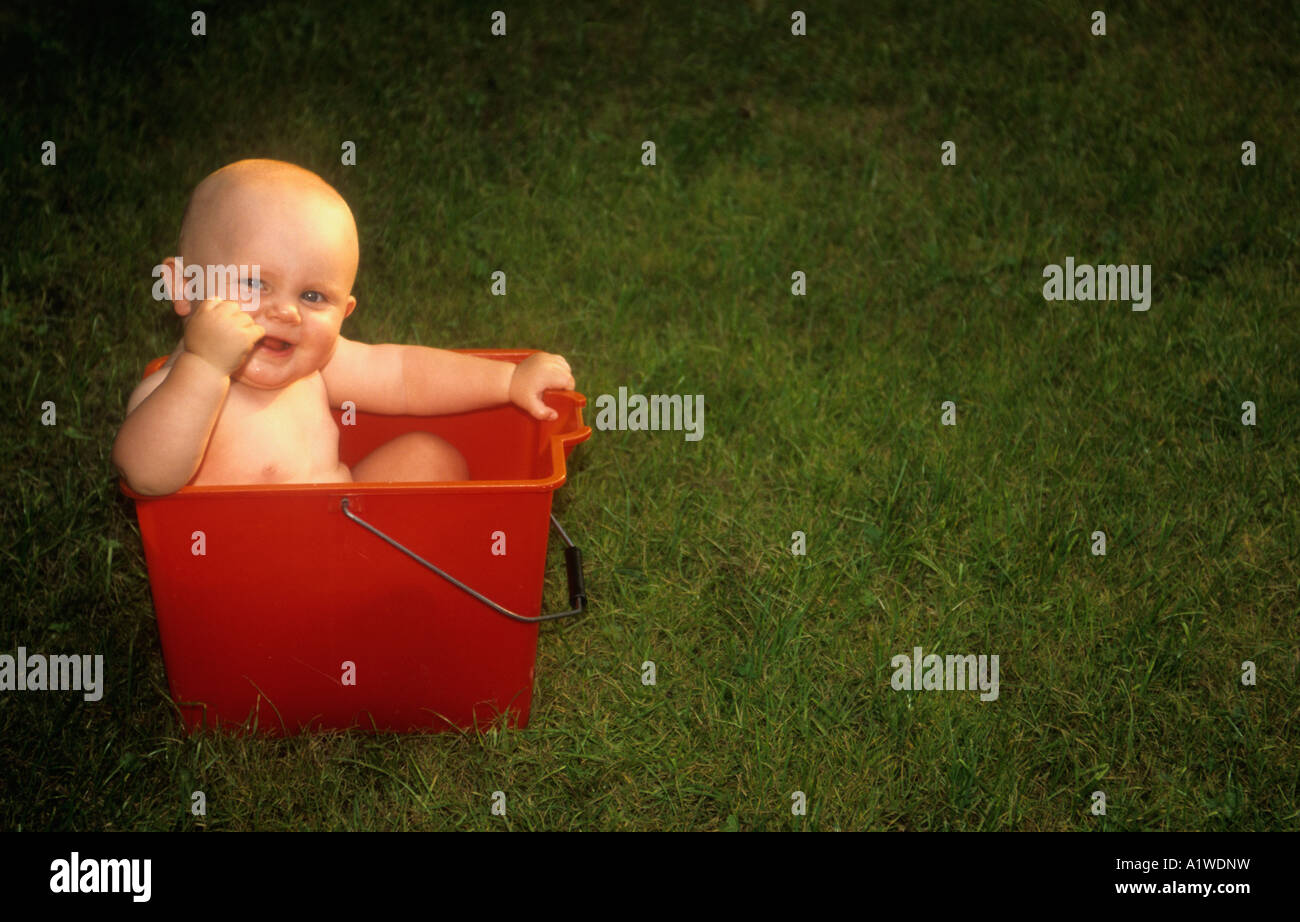 Little Baby Boy Sitting In A Red Plastic Bucket , Outside On A Garden ...