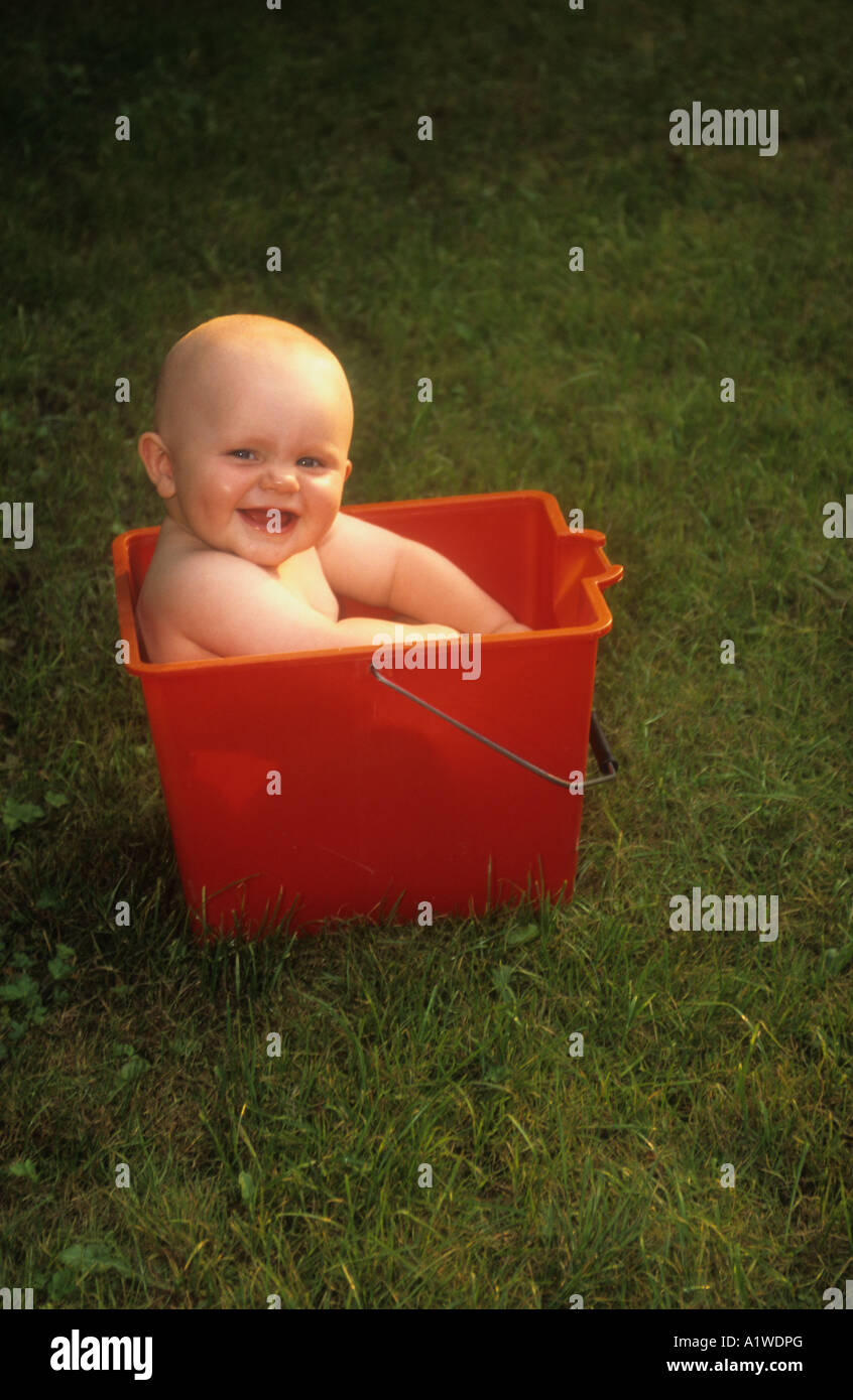 Little Baby Boy Sitting In A Red Plastic Bucket , Outside On A Garden ...