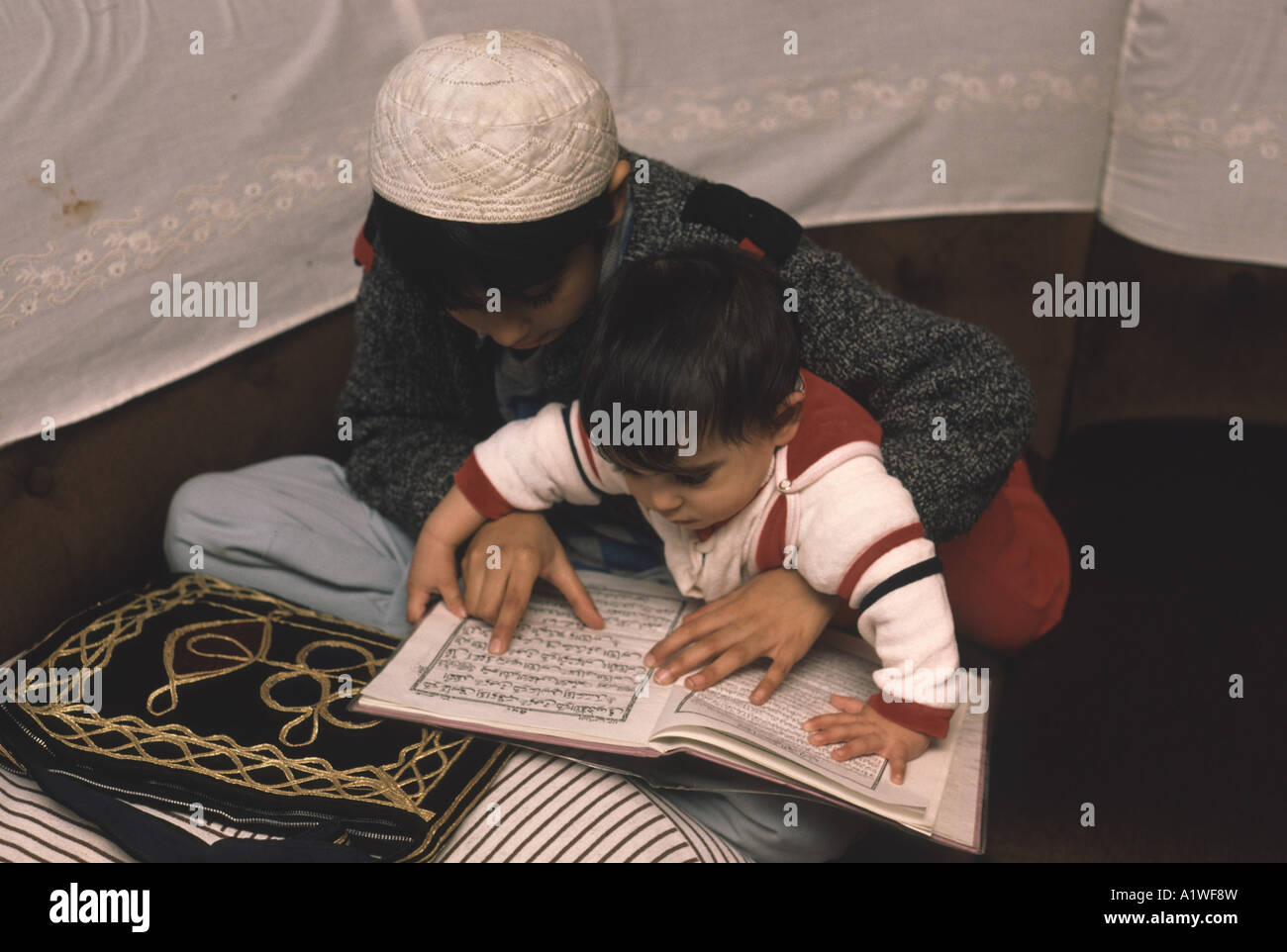Young Muslim boy reading scriptures at home with his baby brother Stock ...