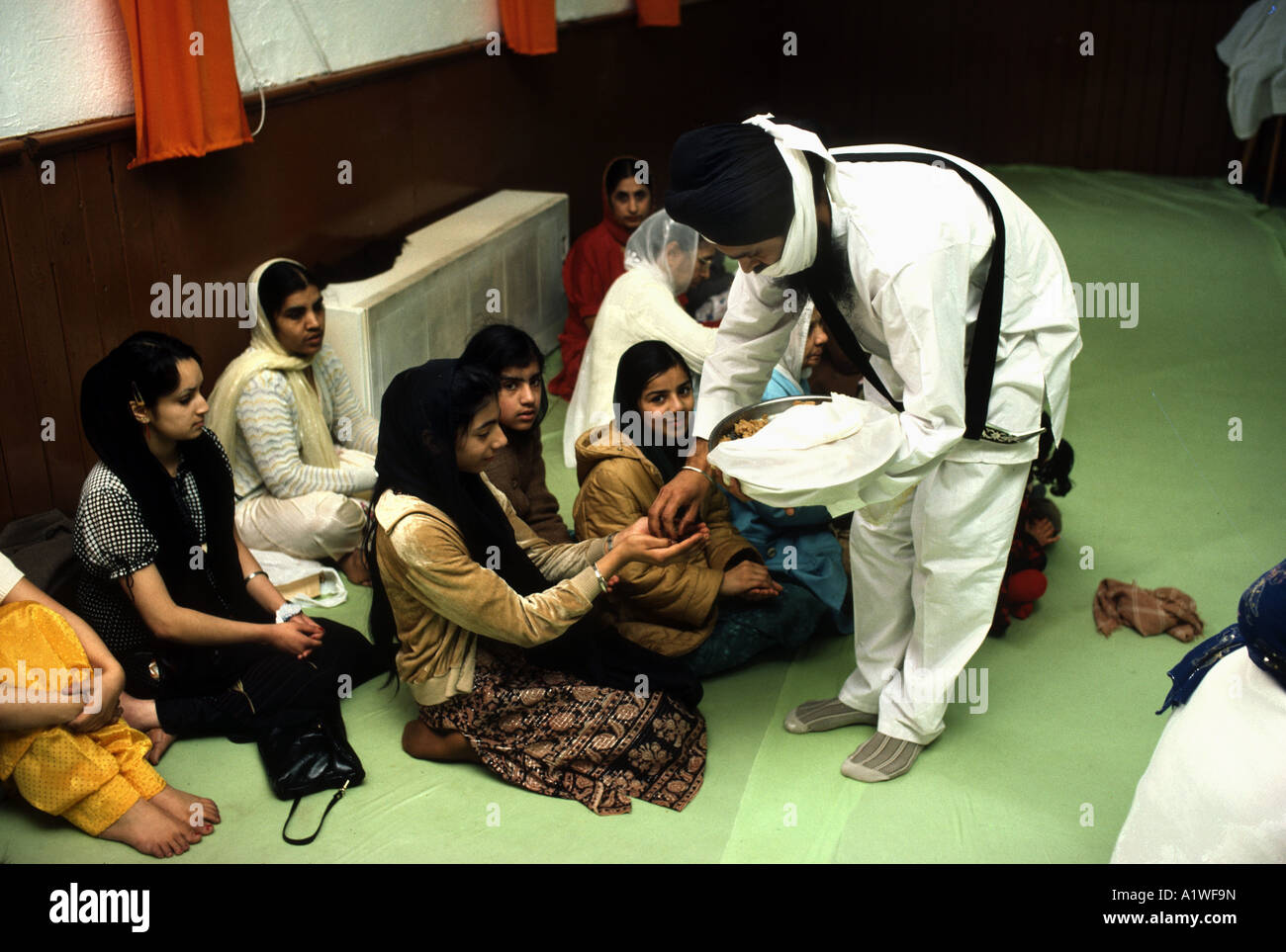 Sikh man serving serving sweets to the women after ceremony held in the ...