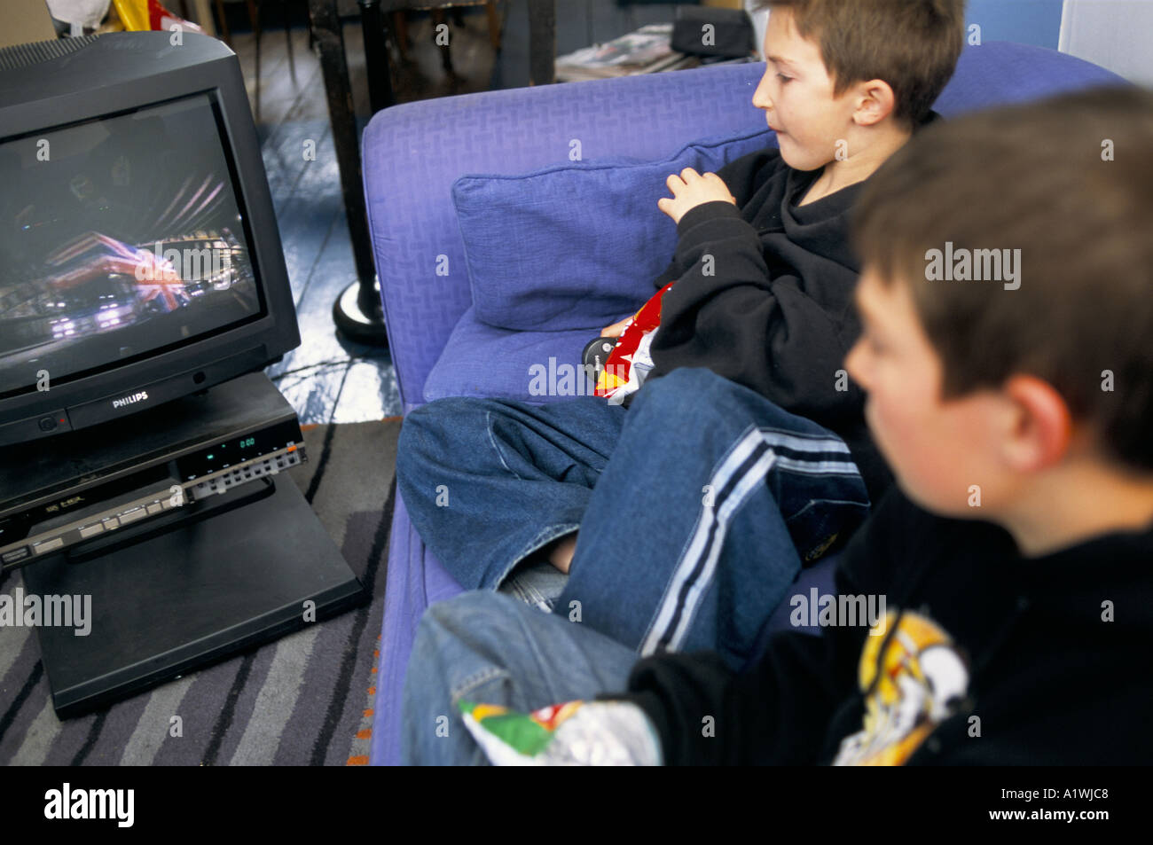 BOYS SITTING ON SOFA EATING CRISPS AND WATCHING TV 2001 Stock Photo - Alamy