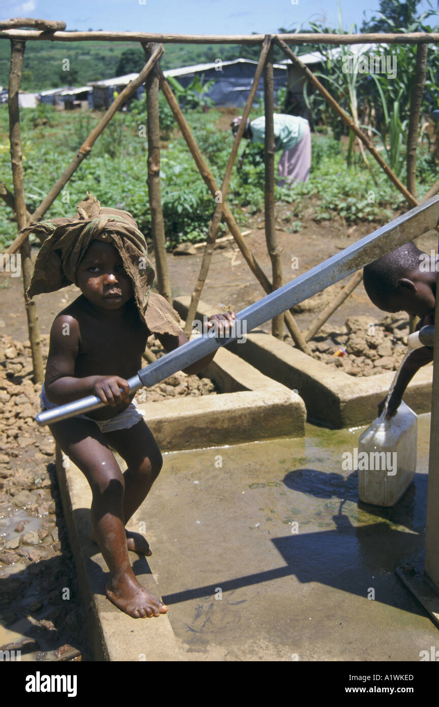 CHILDREN PUMP WATER AT TAP STAND DISPLACED CAMP 1999 Stock Photo - Alamy