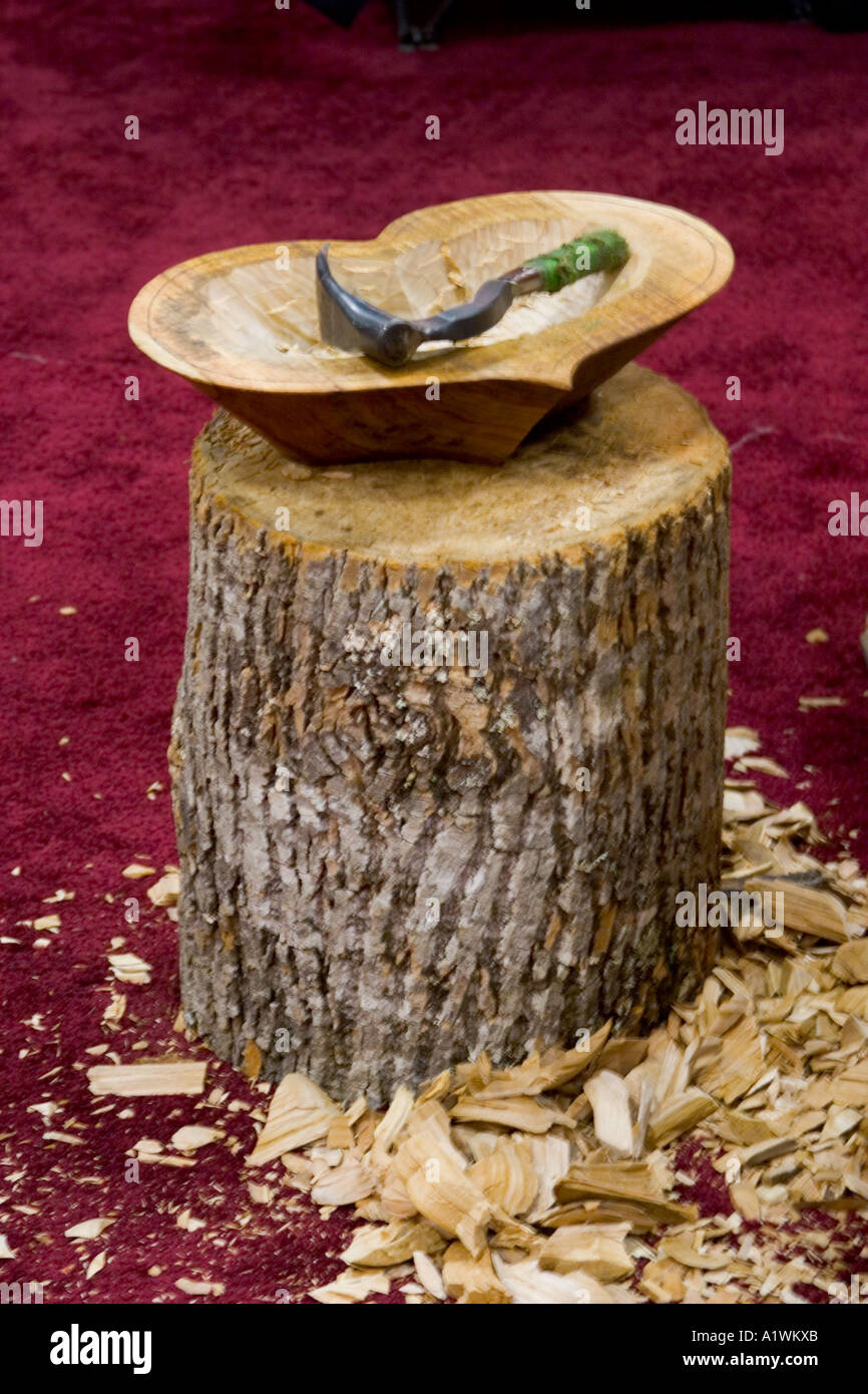 A tool resting on a partially made bowl. A tree trunk is the working ...