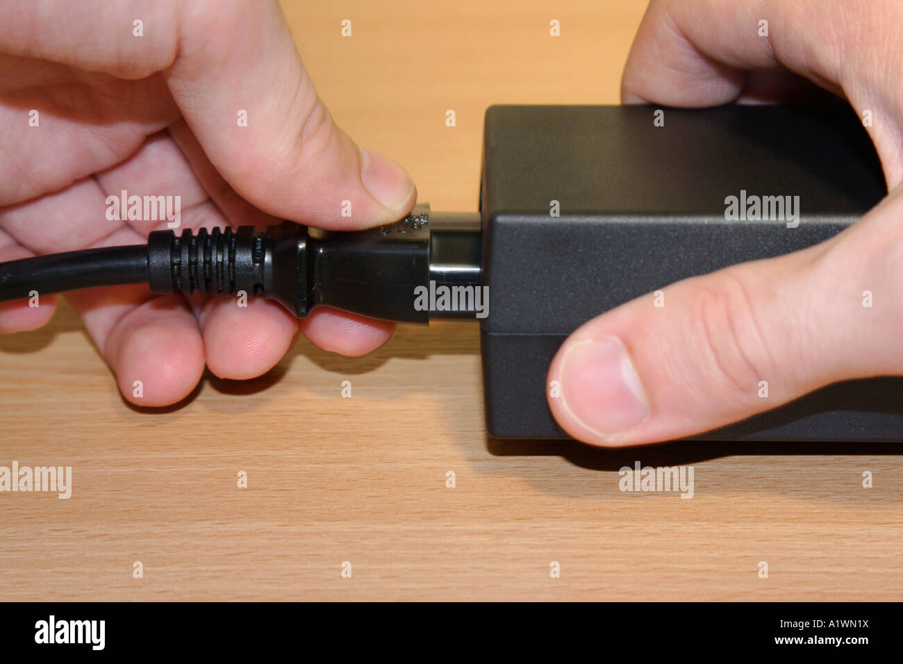 Person plugging cable into power adapter Stock Photo - Alamy