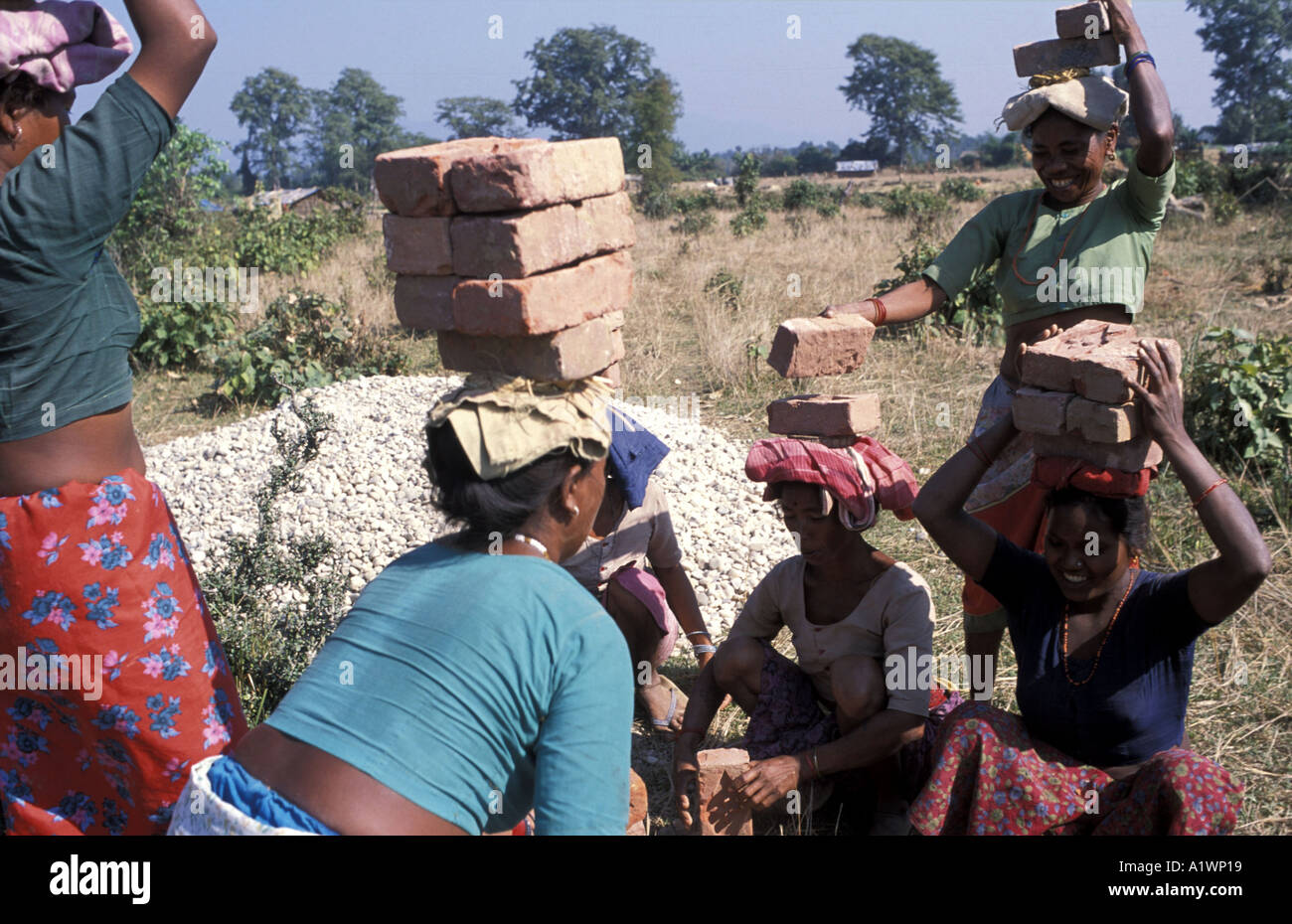 Women brick carriers picking up bricks and carrying them on their heads ...