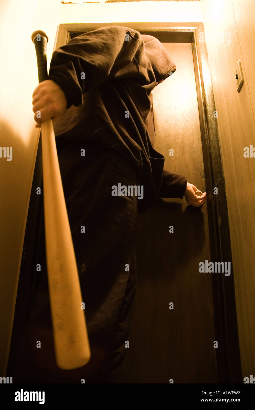 A hooded figure with a baseball bat stands at a doorway Stock Photo - Alamy