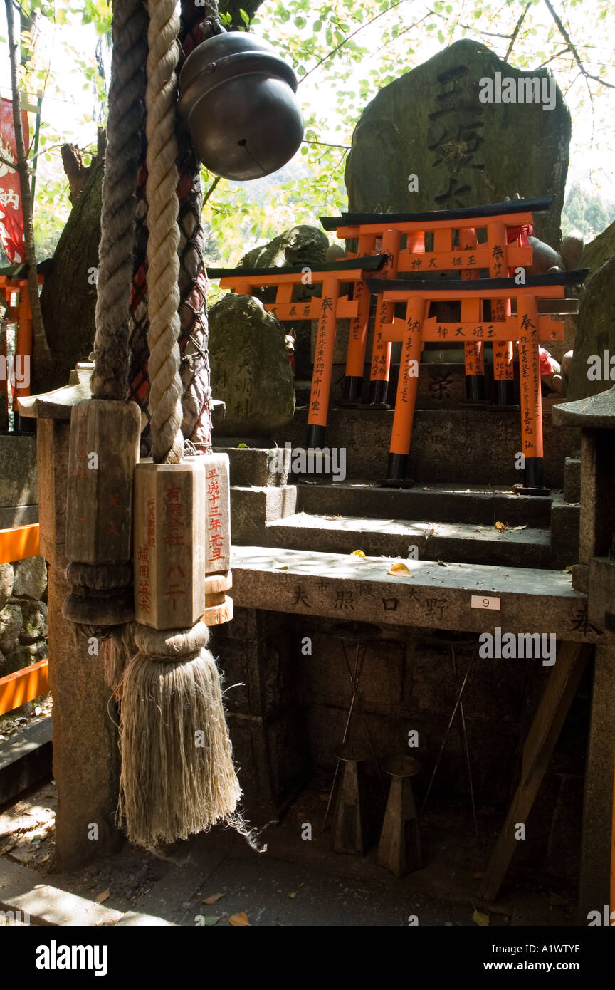 A rope hangs from a bell in front of miniature torii gates at Fushimi ...