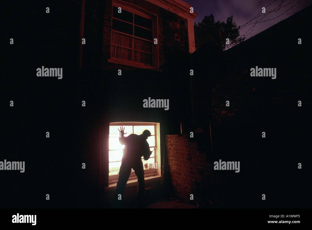 Thief breaking into a home by forcing a rear window. Islington, London ...