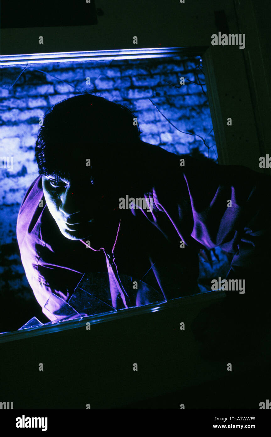 MAN REACHING THROUGH SMASHED WINDOW OF DOOR TO LET HIMSELF INTO ...