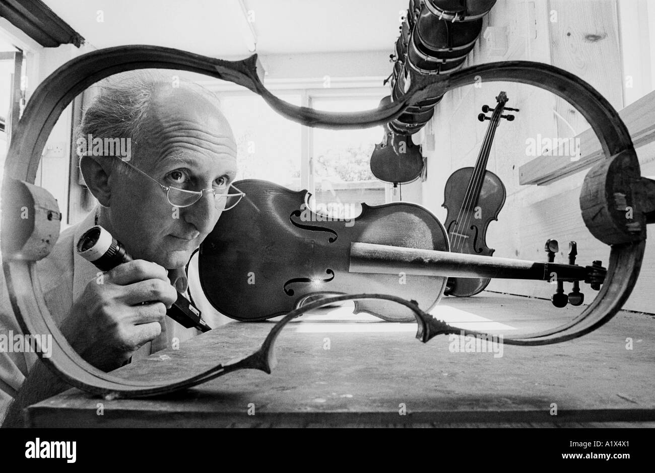 Violin restorer examines an old instrument using an endoscope UK Stock ...