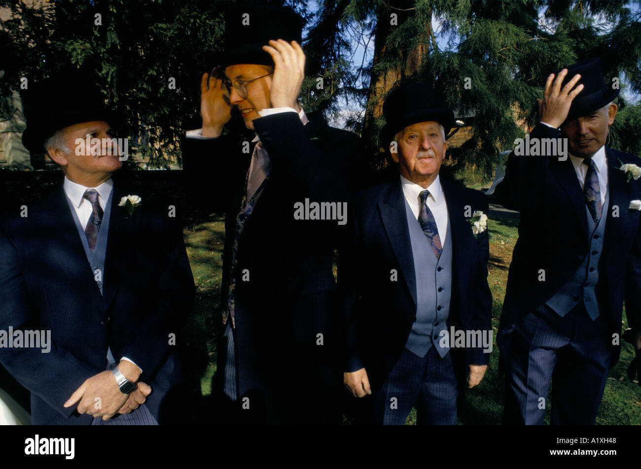 GROUP OF MEN STANDING TOGETHER OUTSIDE WEARING WEDDING SUITS ADJUSTING ...