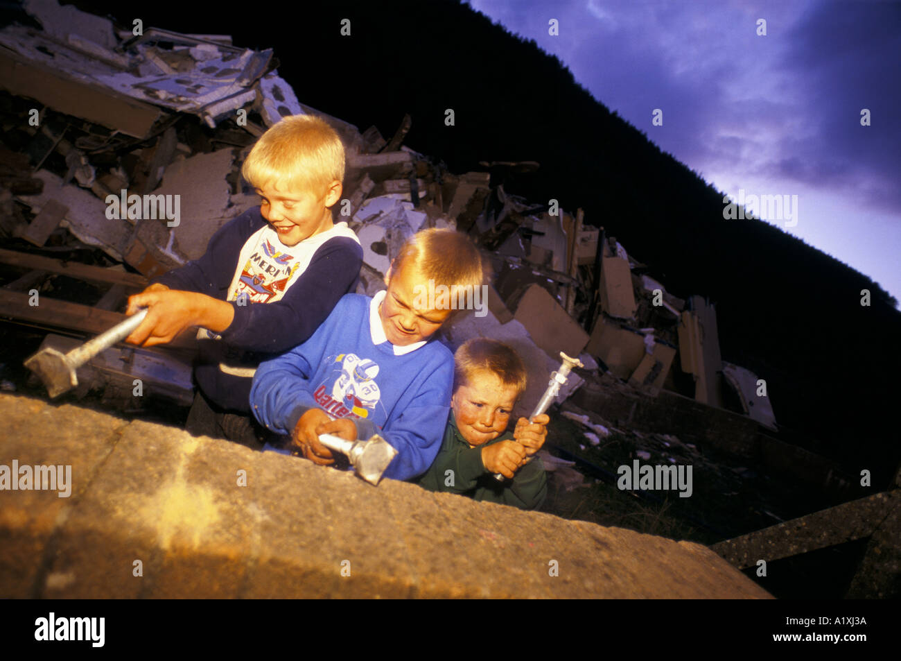 CHILDREN PLAYING WITH METAL JUNK SMASHING UP A WALL HANGING ABOUT IN ...