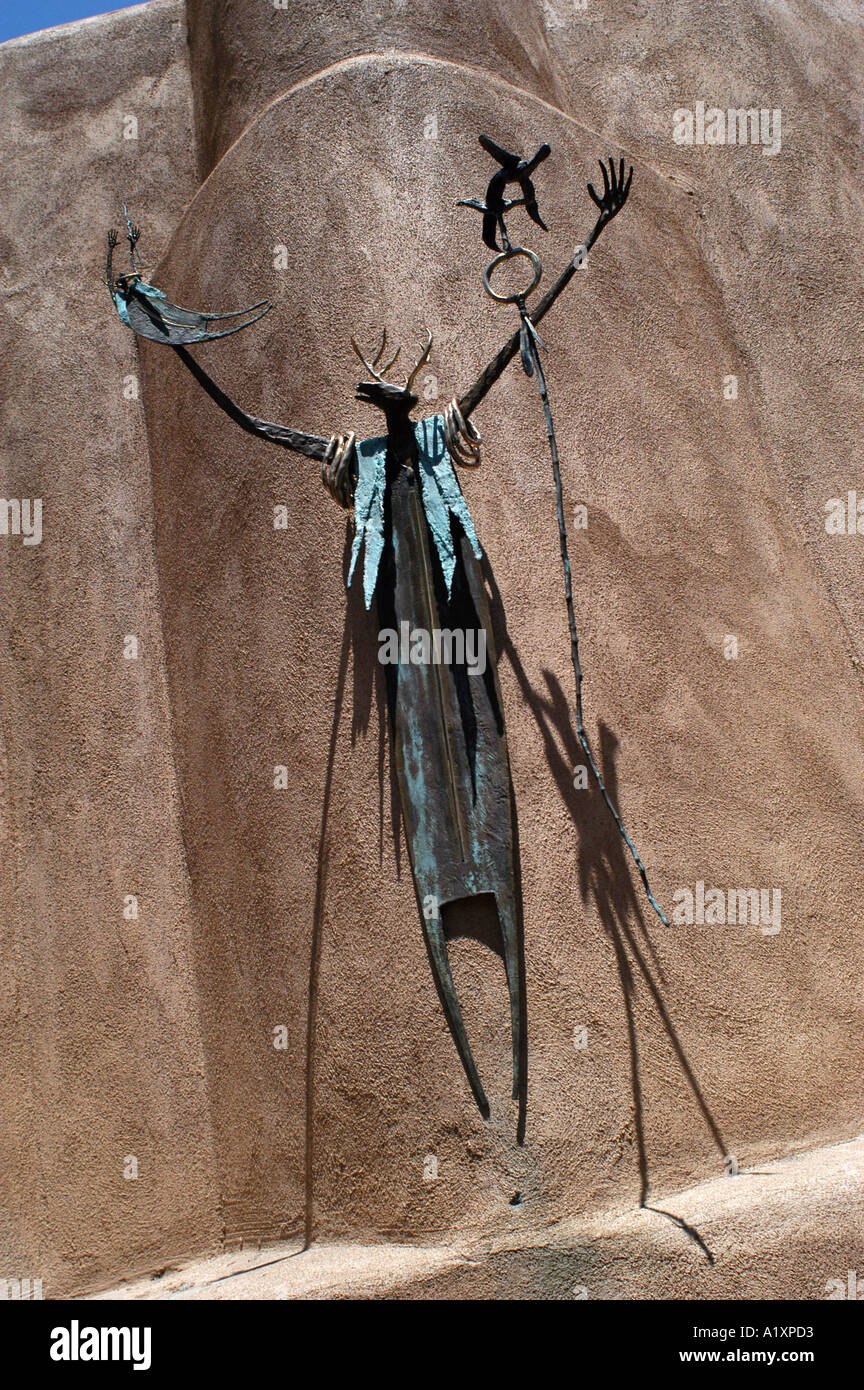 A spindly human figure like sculpture with a hart head its arms raised ...