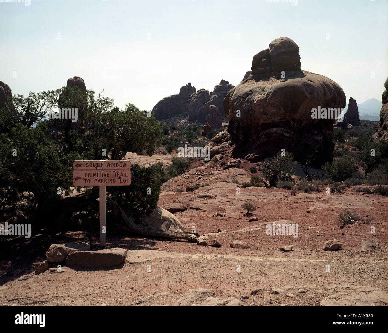 A direction sign at Arches National Monument on dry red earth near ...