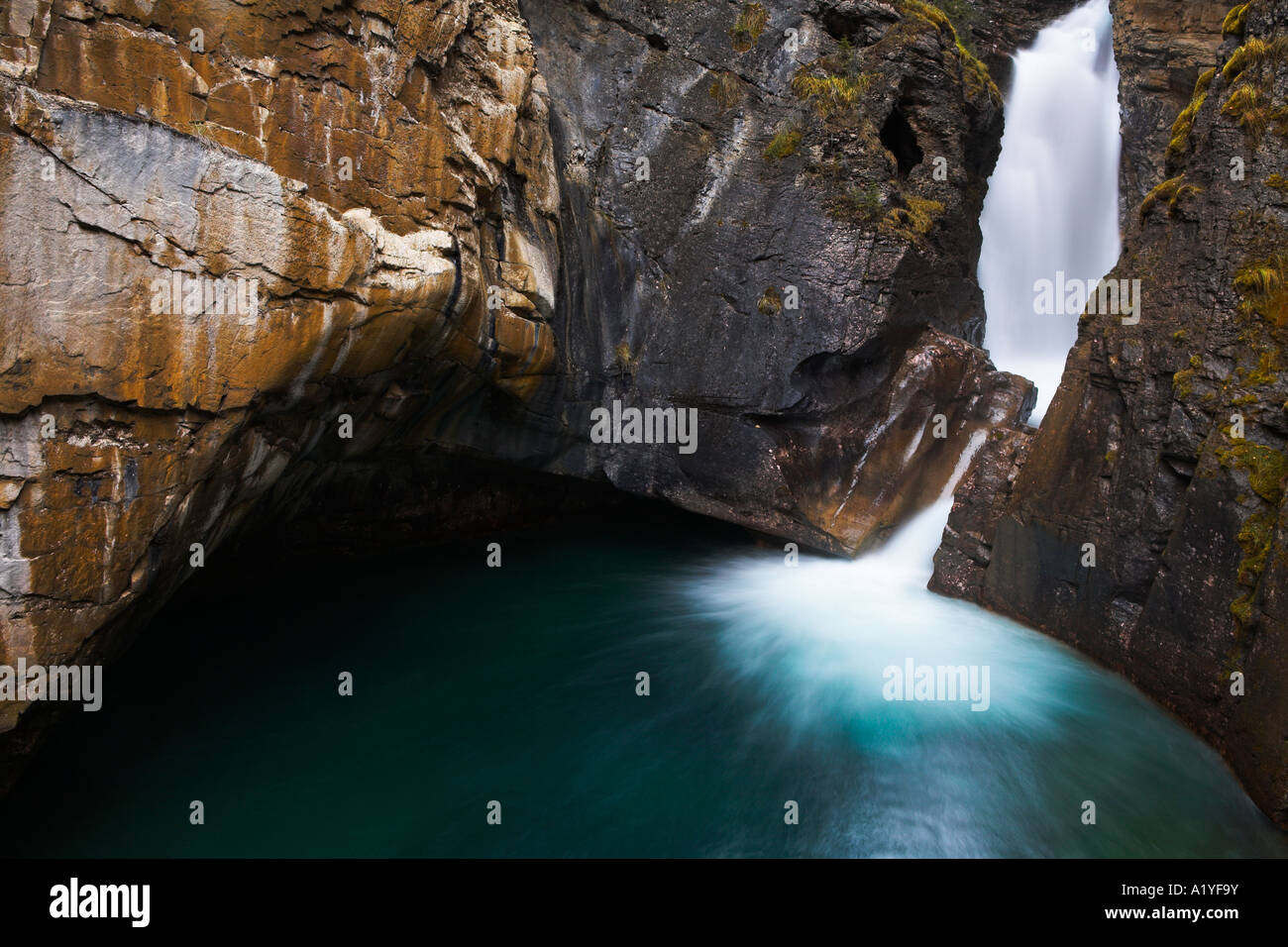 A raging waterfall plunges through rock to a circular pool at Johnston ...