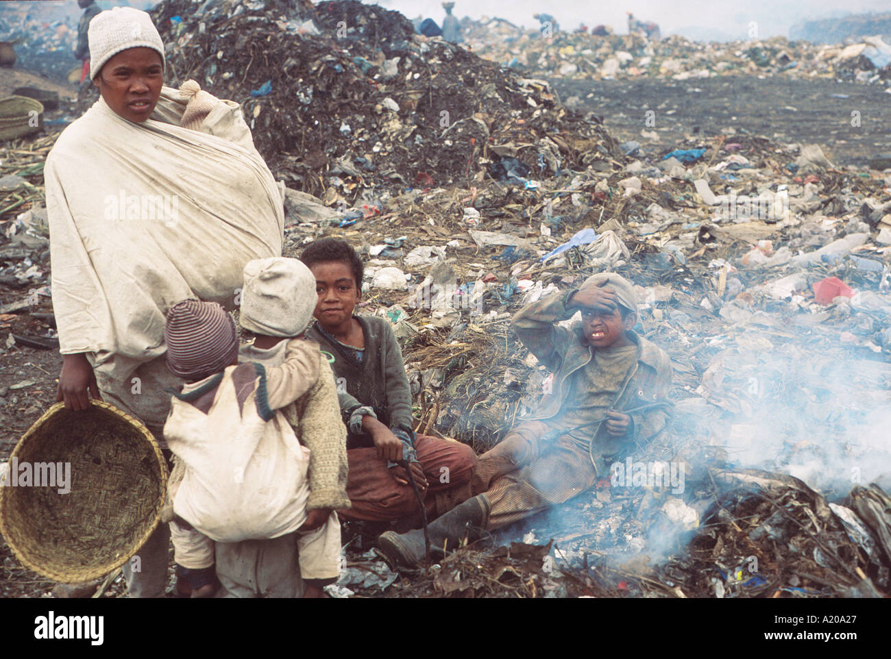 poor mother and children taking a break from scavenging in garbage dump ...