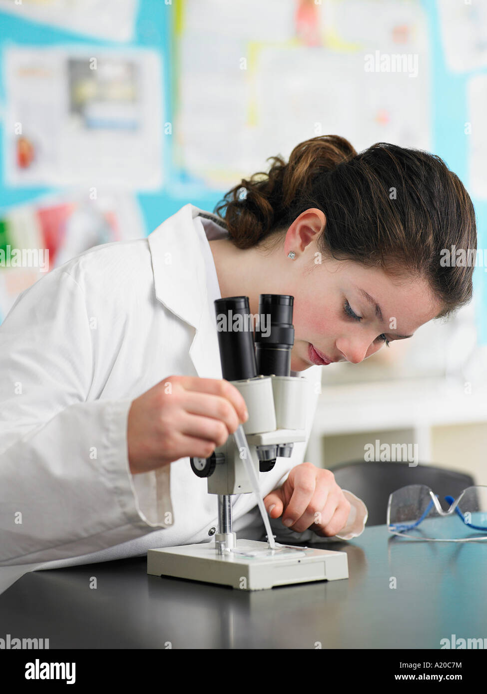 Teenage girl using microscope in classroom Stock Photo - Alamy