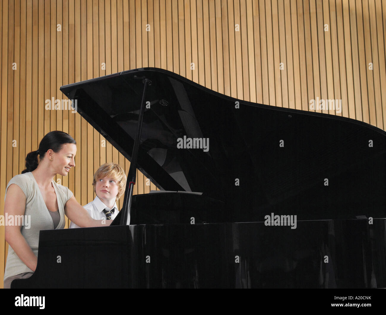 Teacher with student sitting at piano in music class Stock Photo - Alamy