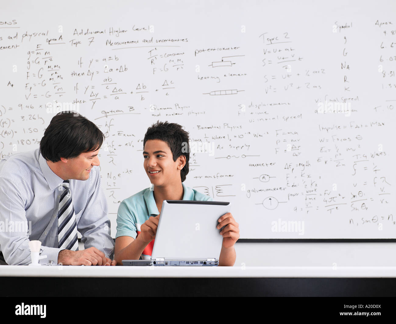 Teacher and student using laptop sitting in physics classroom Stock ...
