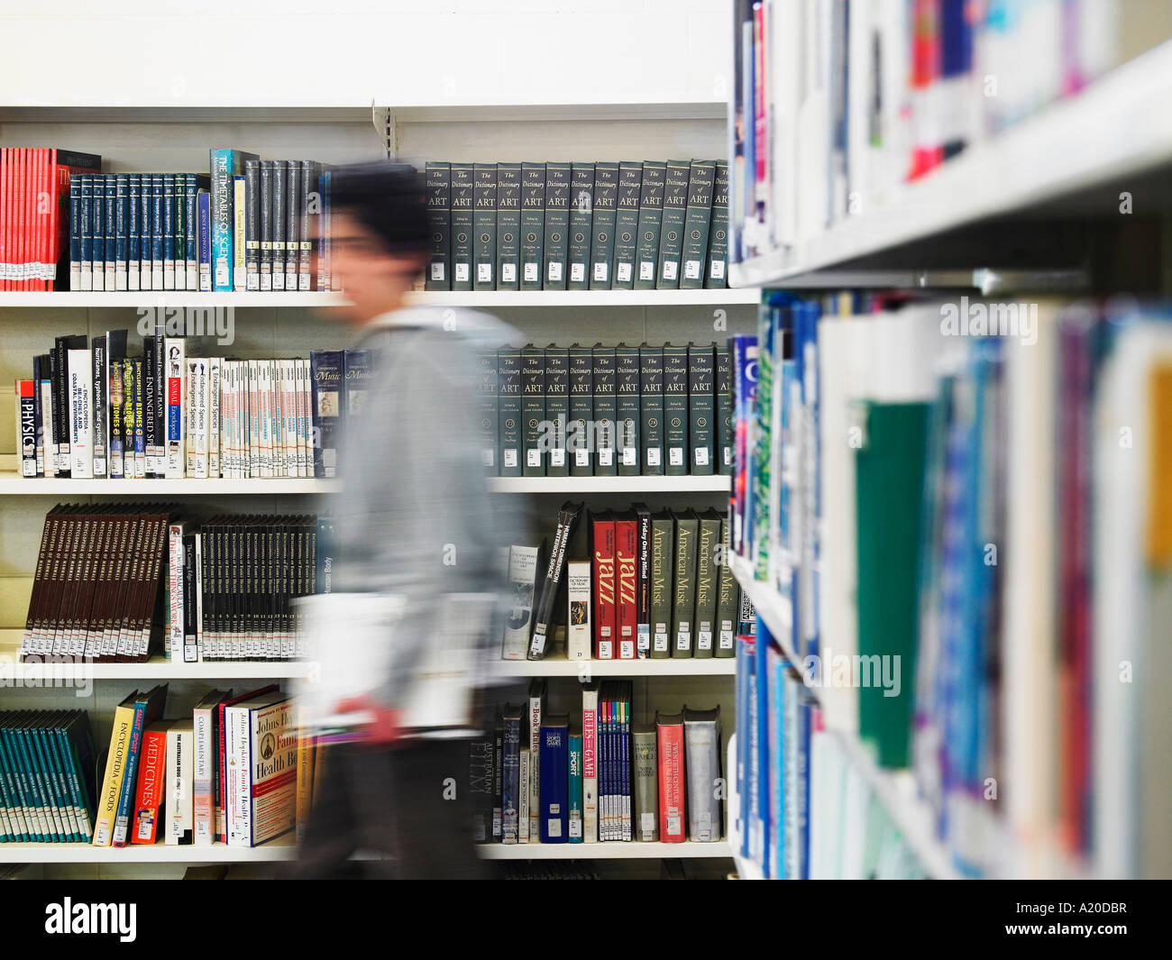 Teenage boy walking through library, motion blur Stock Photo - Alamy