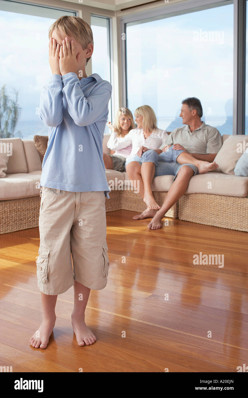 Boy standing, Hiding Face from Family in Background Stock Photo - Alamy