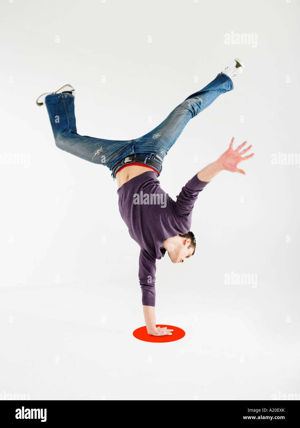 Man doing one handed handstand on red dot Stock Photo - Alamy