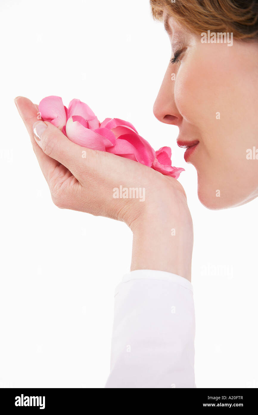 Woman smelling pink rose petals in hand Stock Photo - Alamy