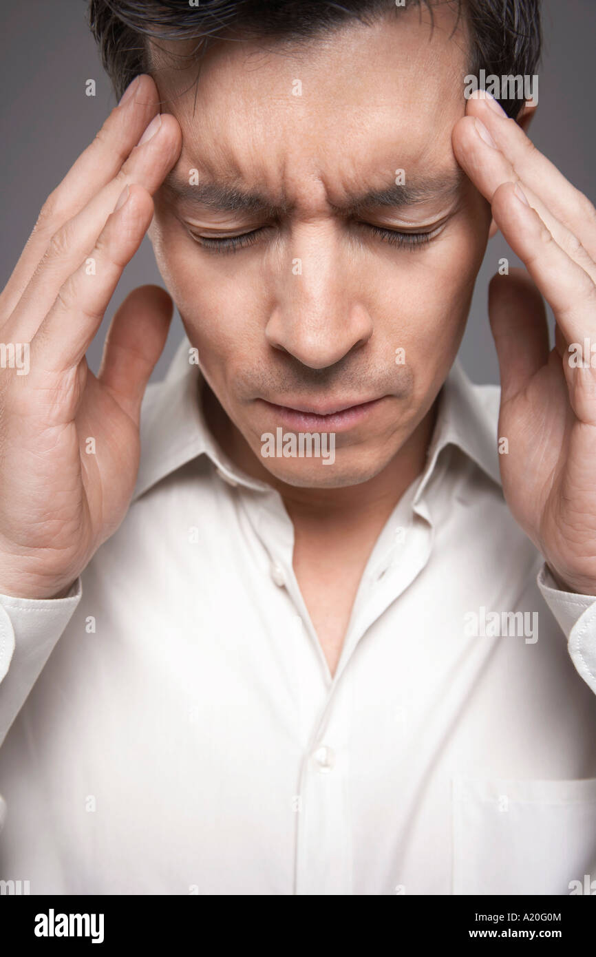 Man with fingers pressed to forehead, close-up Stock Photo - Alamy