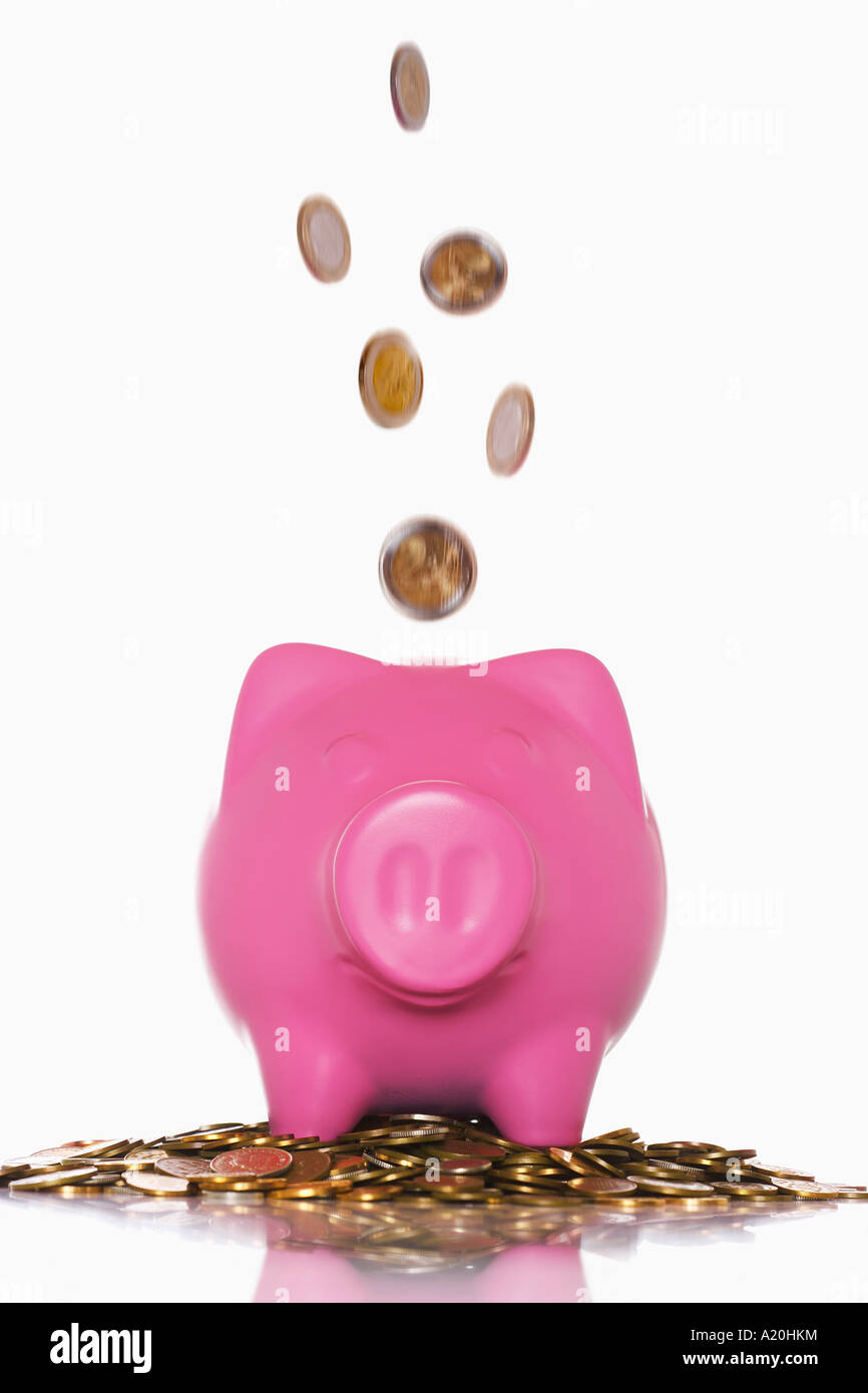 Coins pouring into overflowing piggy bank Stock Photo - Alamy