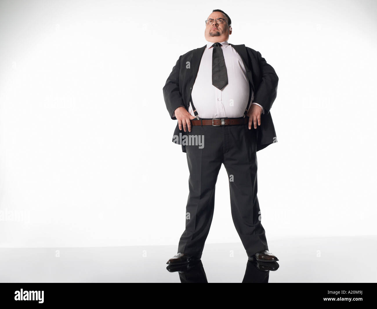 Overweight businessman standing with thumbs in belt Stock Photo - Alamy