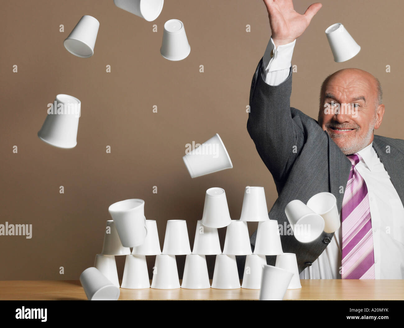Businessman knocking down pyramid of plastic cups Stock Photo - Alamy