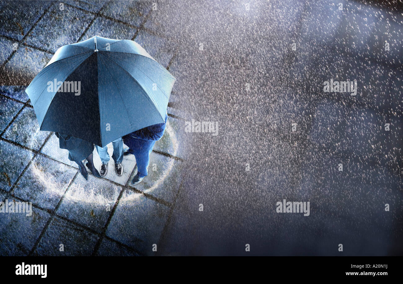 Businesspeople sheltering under umbrella in rain, elevated view Stock ...