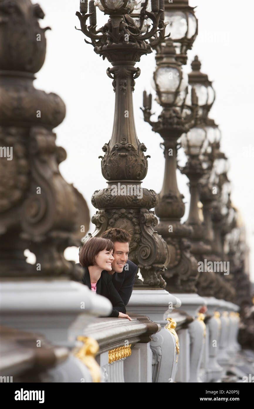 Couple looking over bridge through streetlights Stock Photo - Alamy