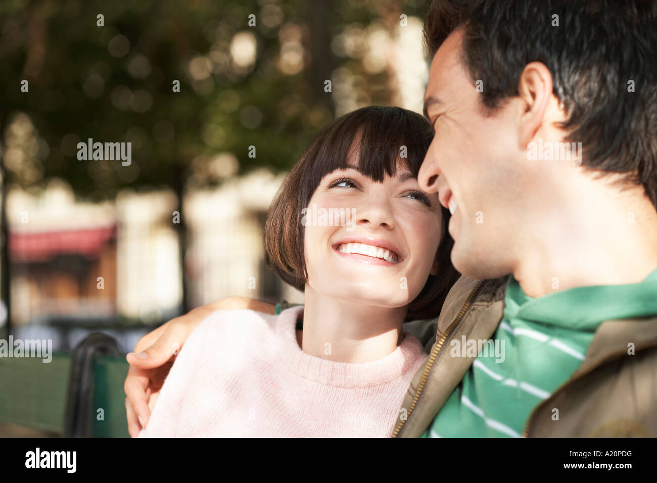 Couple smiling at each other on bench in park, head and shoulders Stock ...