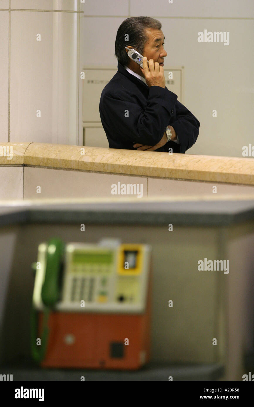 Japanese businessman, known as a salaryman, using his mobile telephone ...
