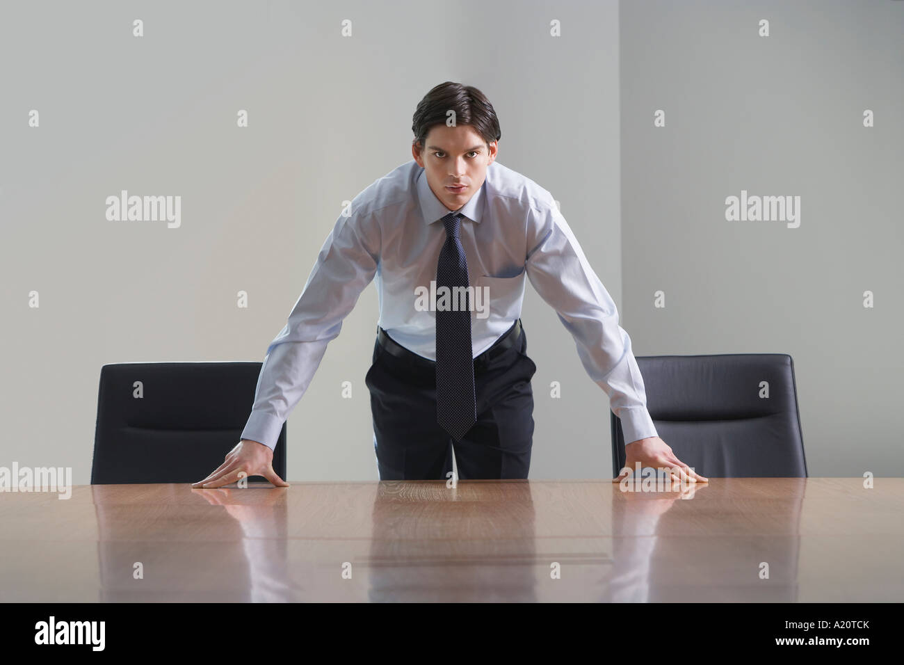 Businessman standing and leaning over conference room table Stock Photo ...