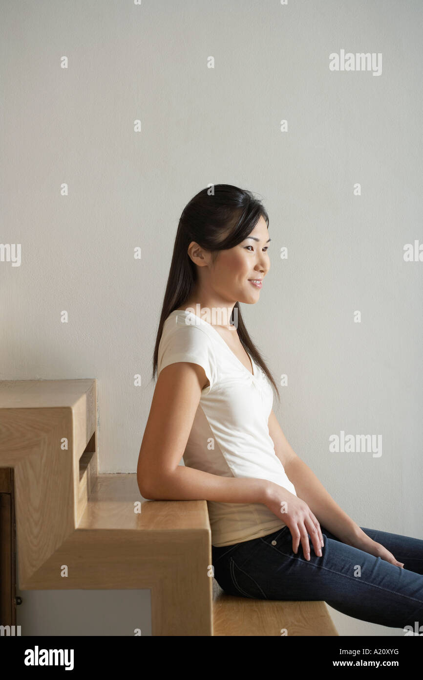 Young Woman Sitting on wooden staircase, side view Stock Photo - Alamy