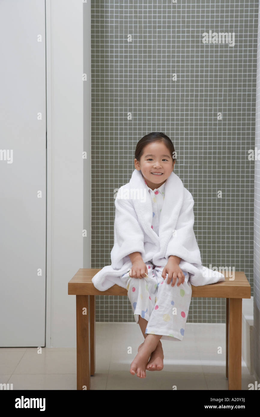 Young Girl wearing bathrobe, Sitting on Bench by Bathtub Stock Photo ...