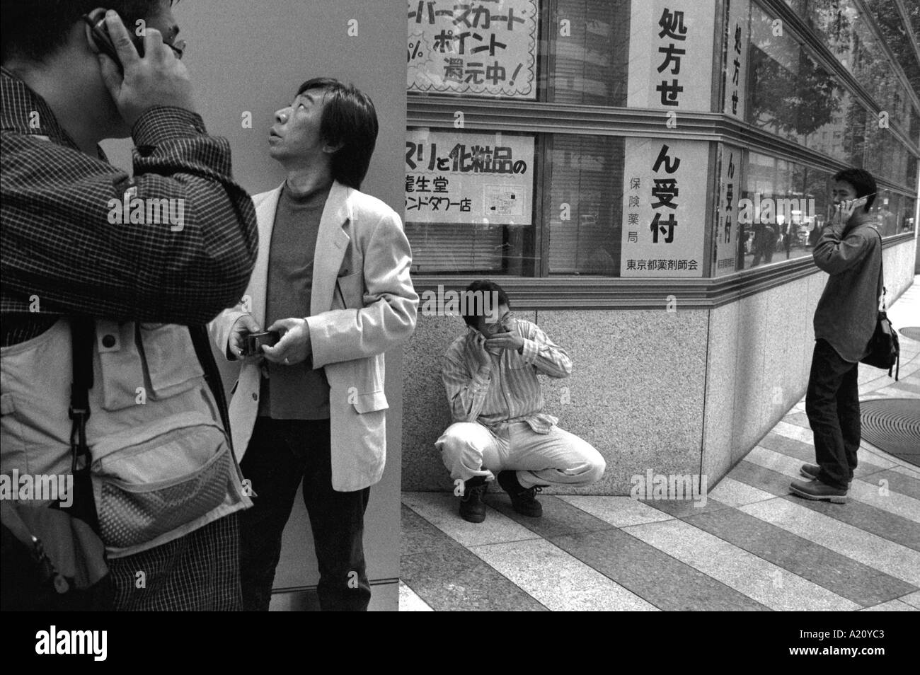 Four Japanese men using their mobile telephones in the Nishi Shinjuku ...