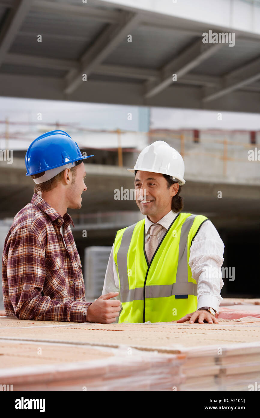 Construction workers talking at building site Stock Photo - Alamy