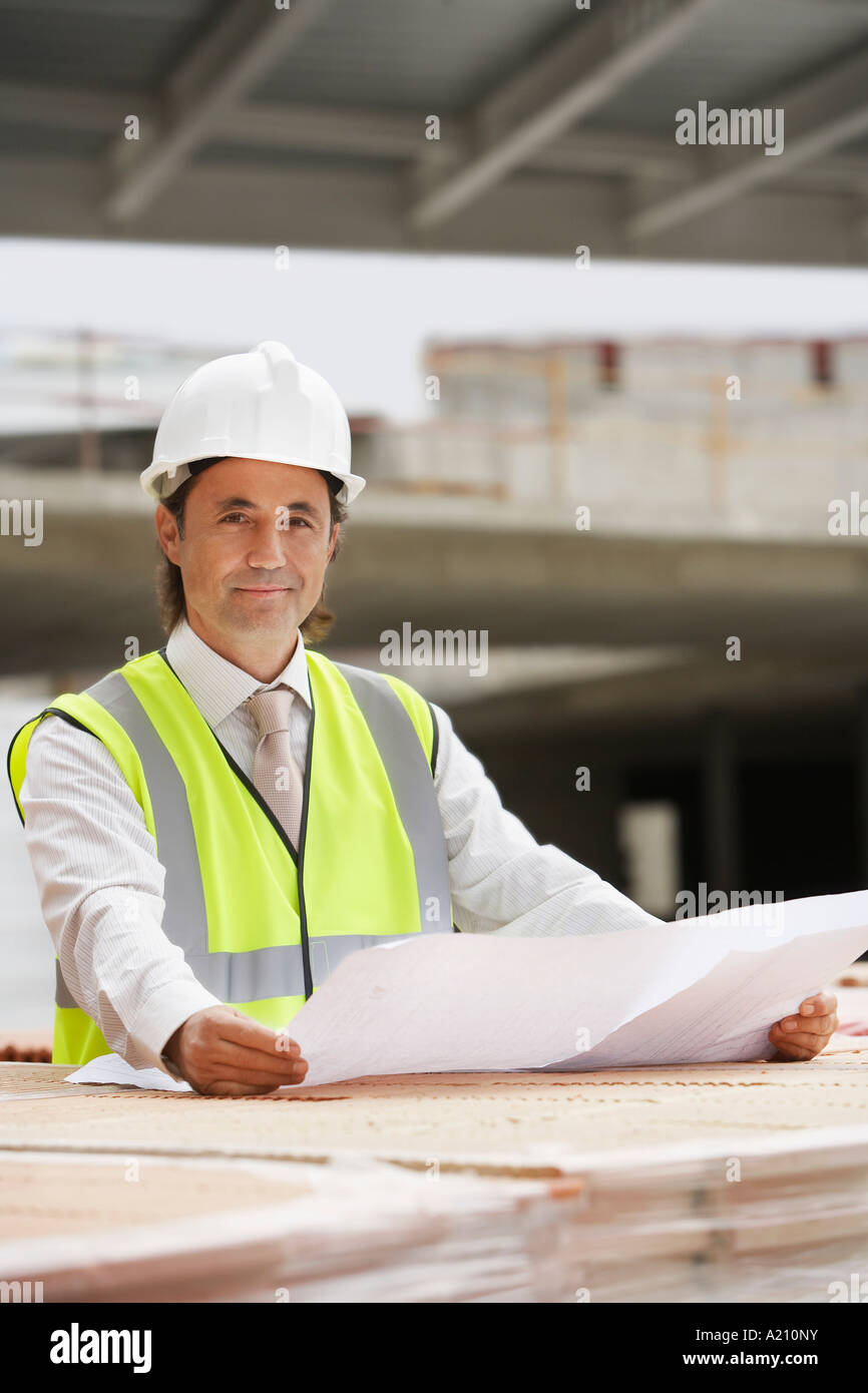Construction worker holding building plans Stock Photo - Alamy