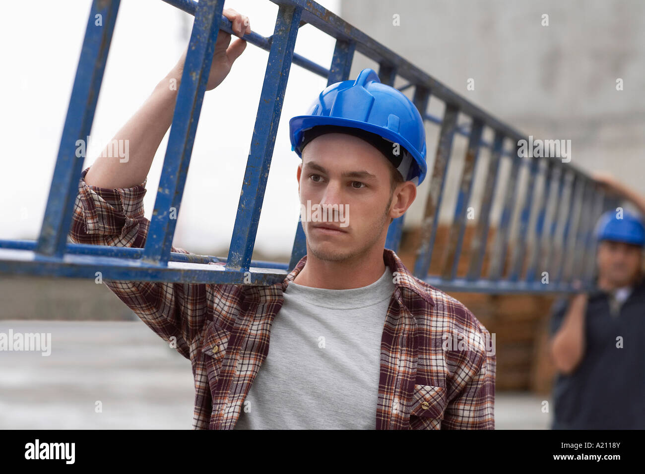 Two construction workers carrying ladder Stock Photo - Alamy