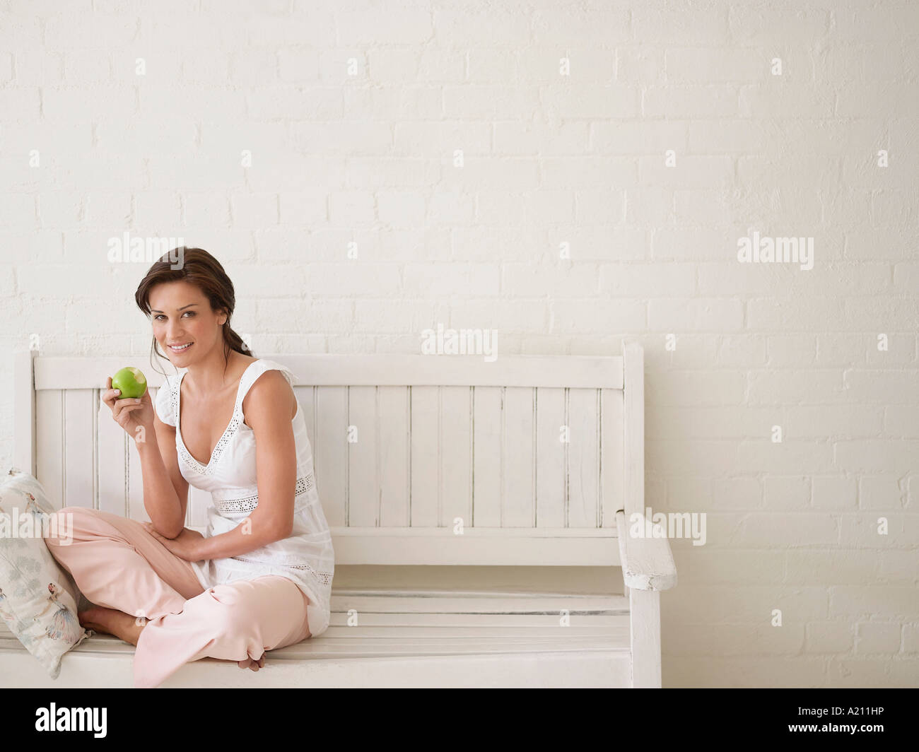 Woman Eating Apple, sitting, cross-legged on bench Stock Photo - Alamy