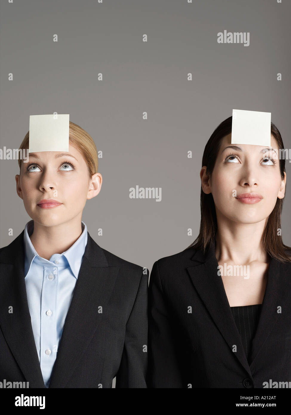 Portrait of two female office workers with sticky notes on forehead ...